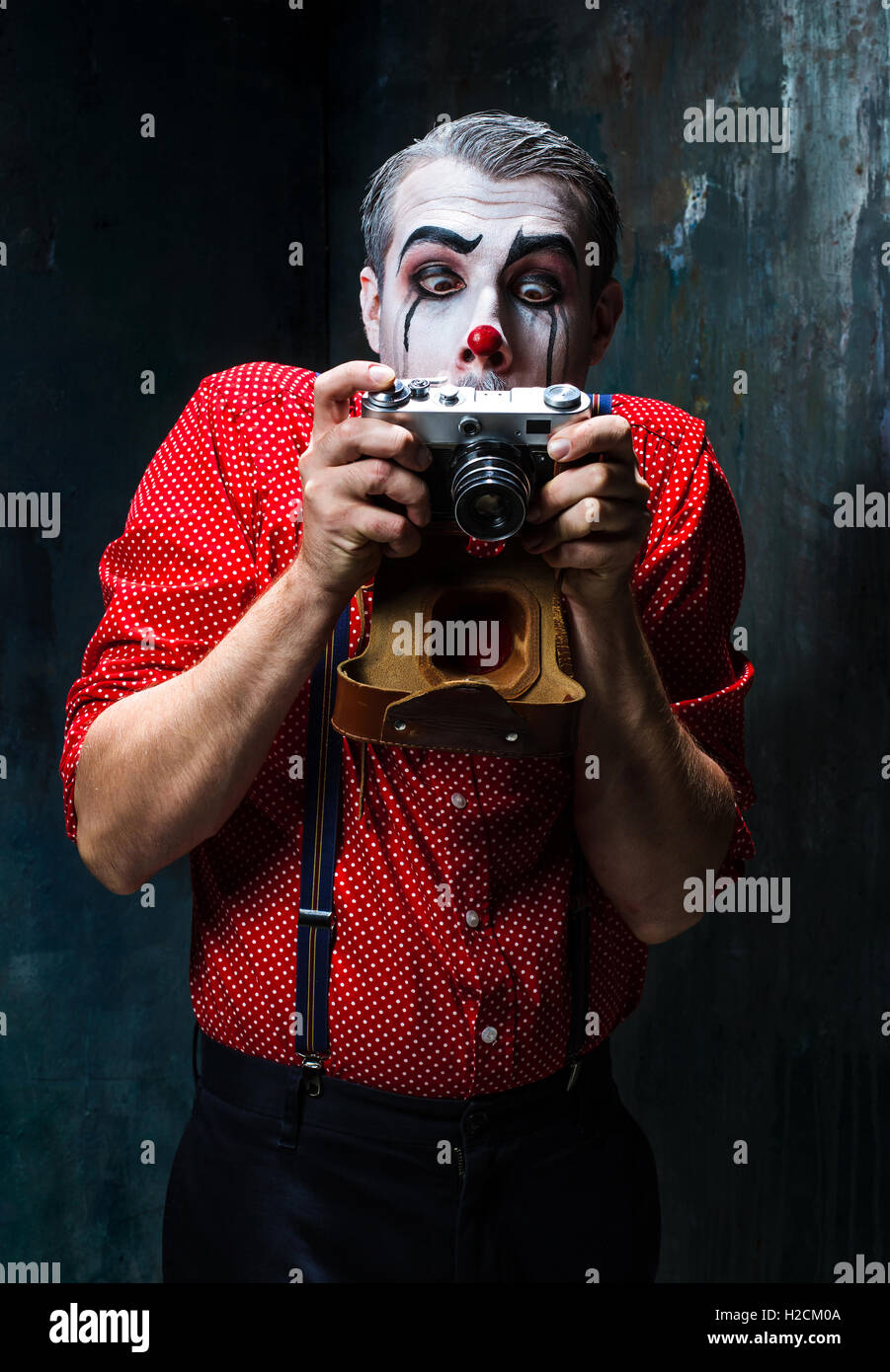 The scary clown and a camera on dack background. Halloween concept ...