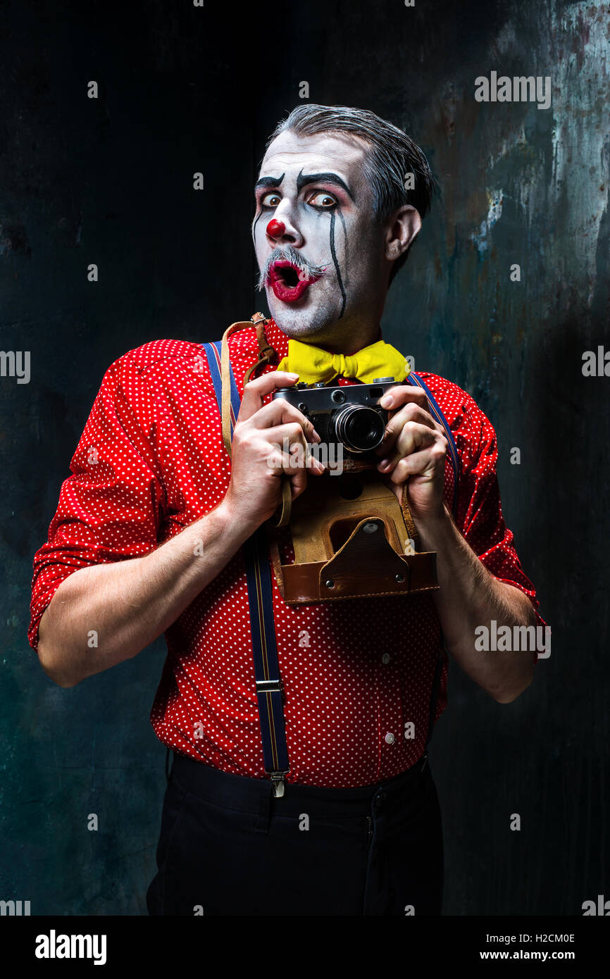 The scary clown and a camera on dack background. Halloween concept ...
