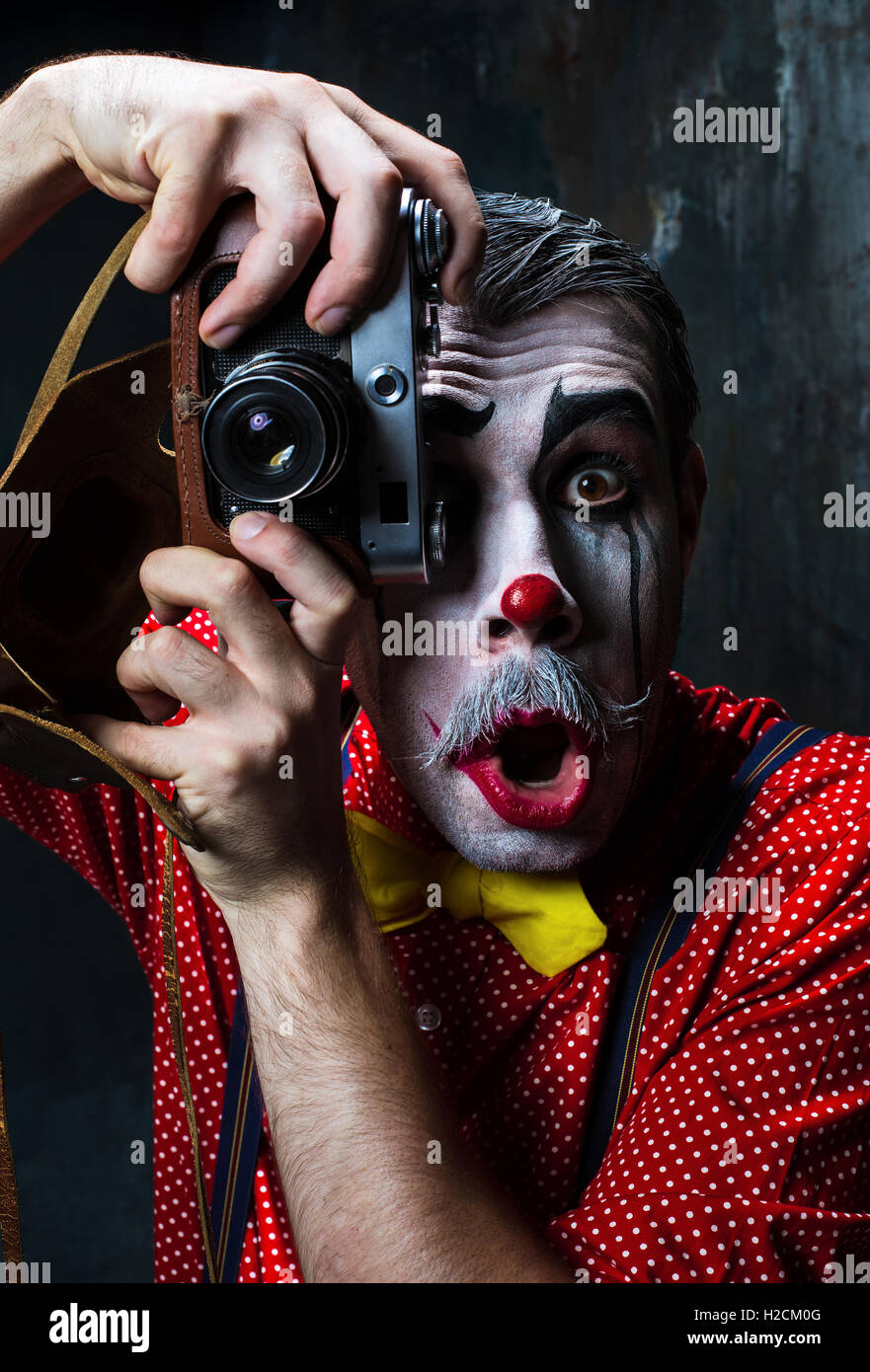 The scary clown and a camera on dack background. Halloween concept ...