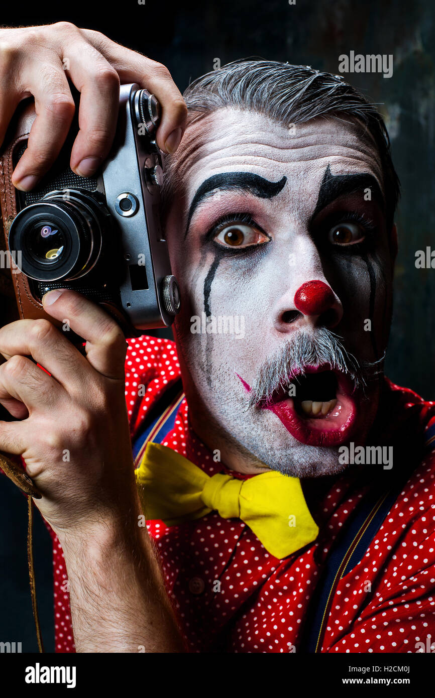 The scary clown and a camera on dack background. Halloween concept ...