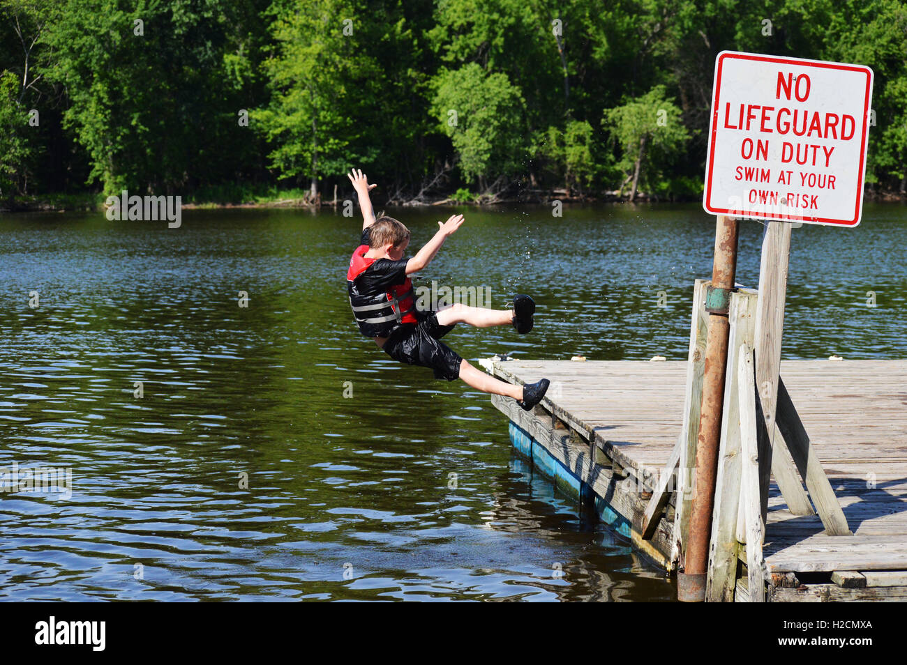 Young boy jumps off dock with warning sign Stock Photo - Alamy