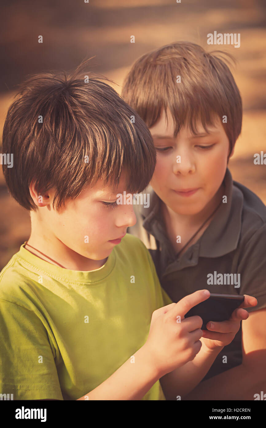 Child little boy playing mobile phone outdoors Stock Photo - Alamy