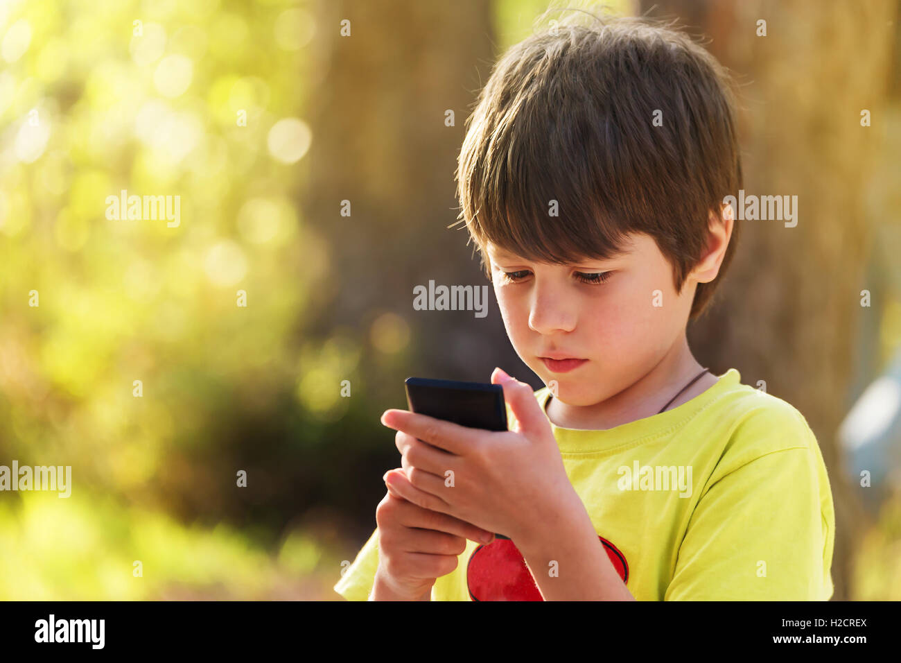 Child little boy playing mobile phone outdoors Stock Photo - Alamy