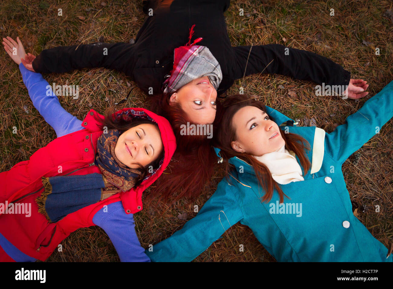 Three young woman lying on an autumn grass outdoors Stock Photo - Alamy