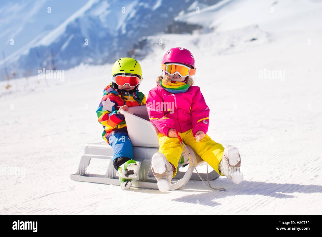 Little girl and baby boy play with snow on sleigh ride in Swiss Alps ...