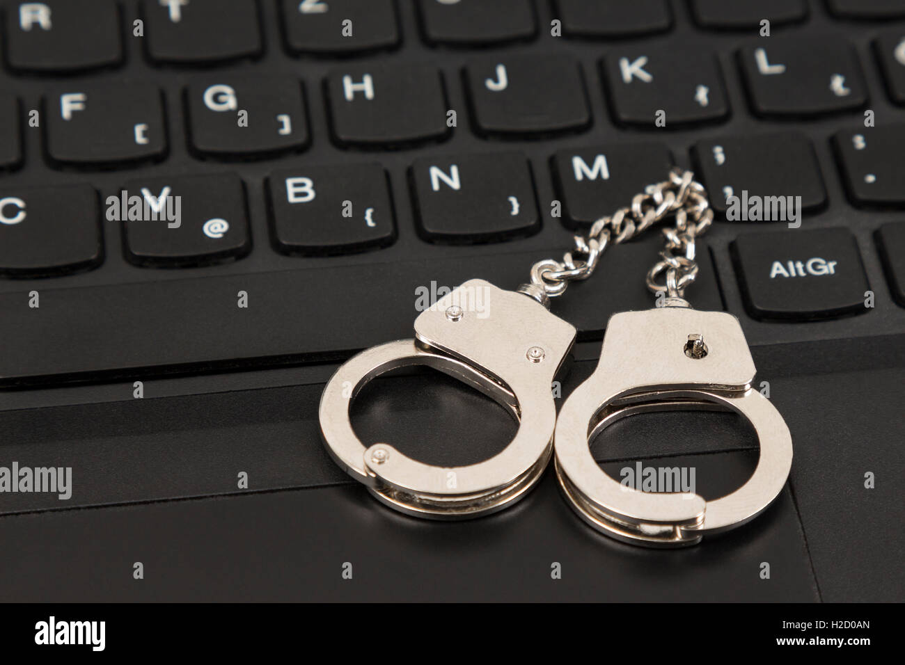 Cybercriminal concept. Keychain handcuffs on the black computer ...
