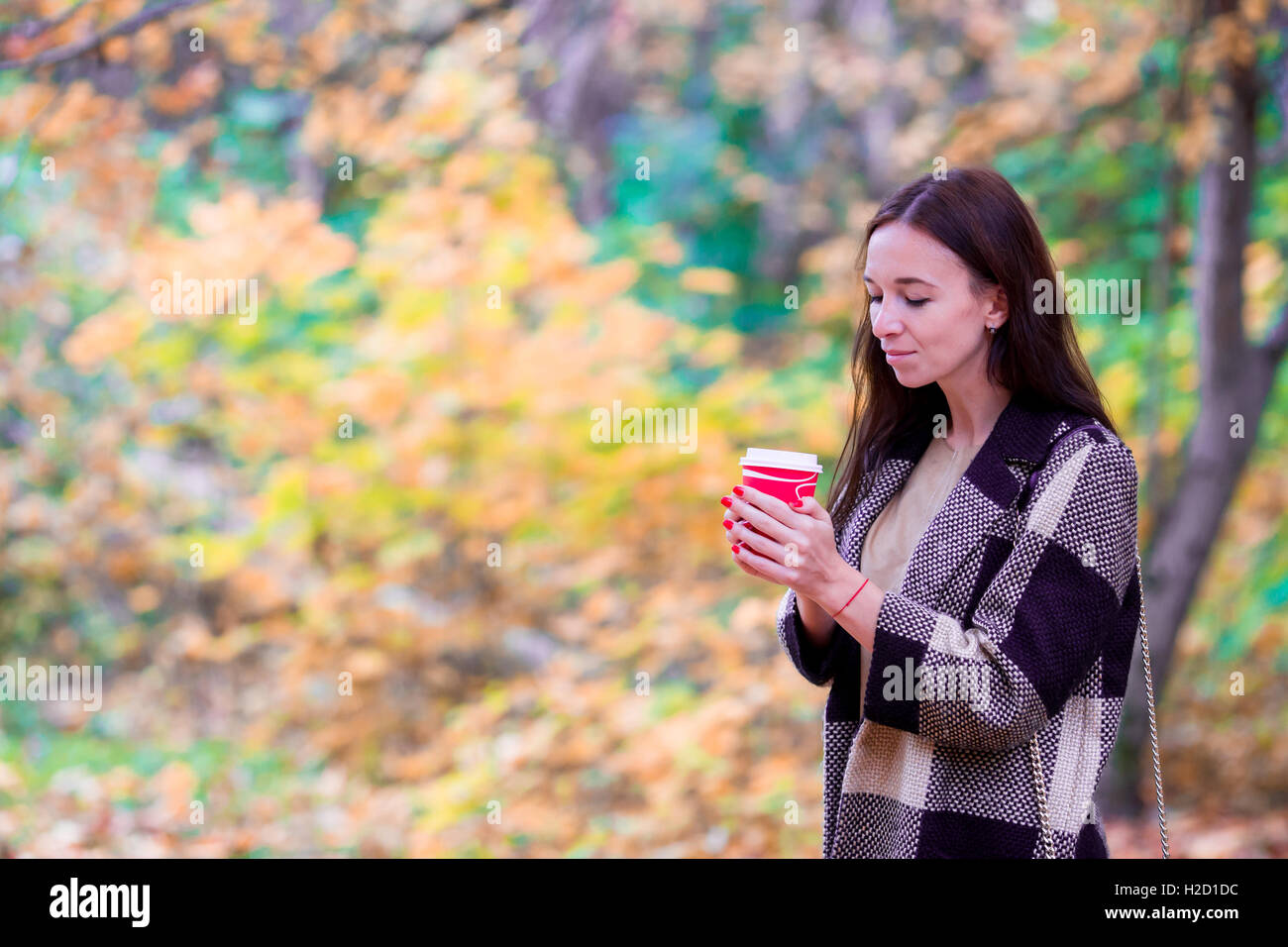 Beautiful woman drinking coffee in autumn park under fall foliage ...