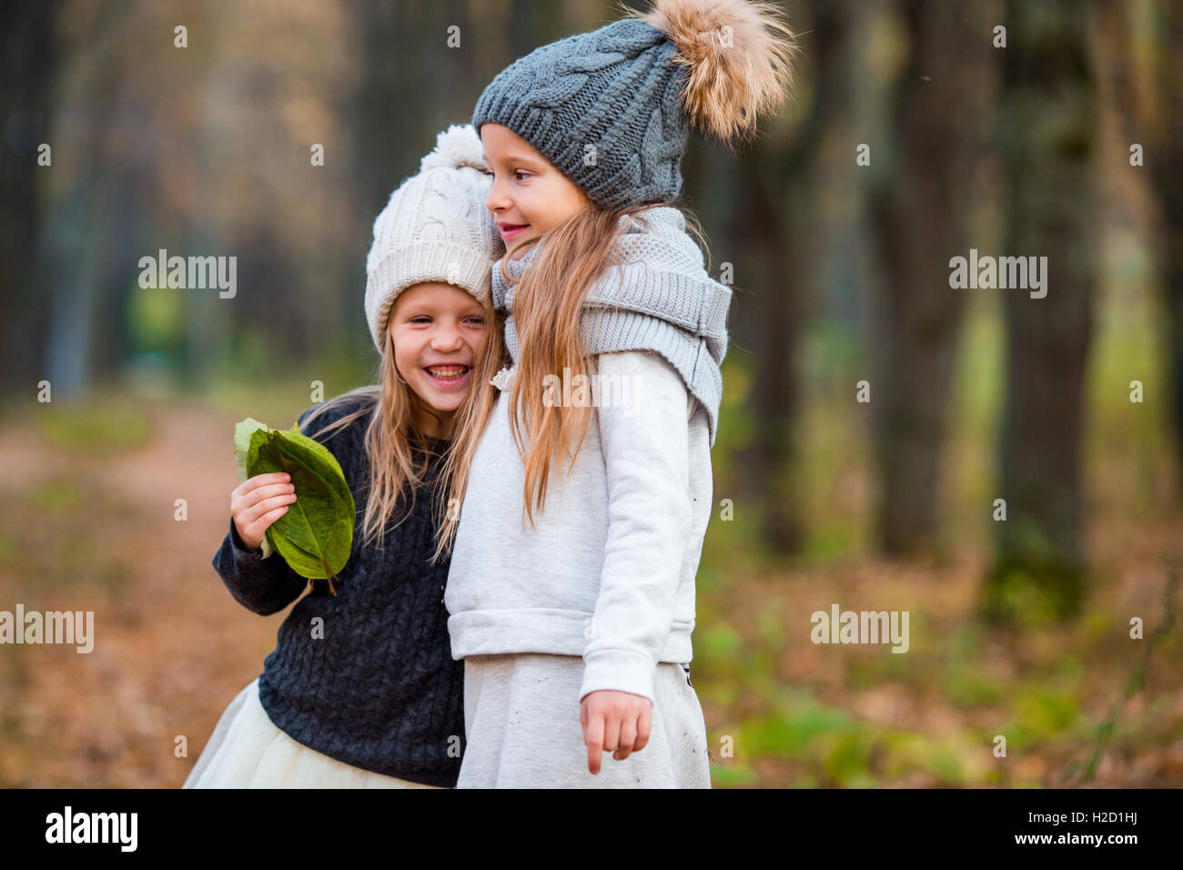 Two adorable girls in forest at warm sunny autumn day Stock Photo - Alamy
