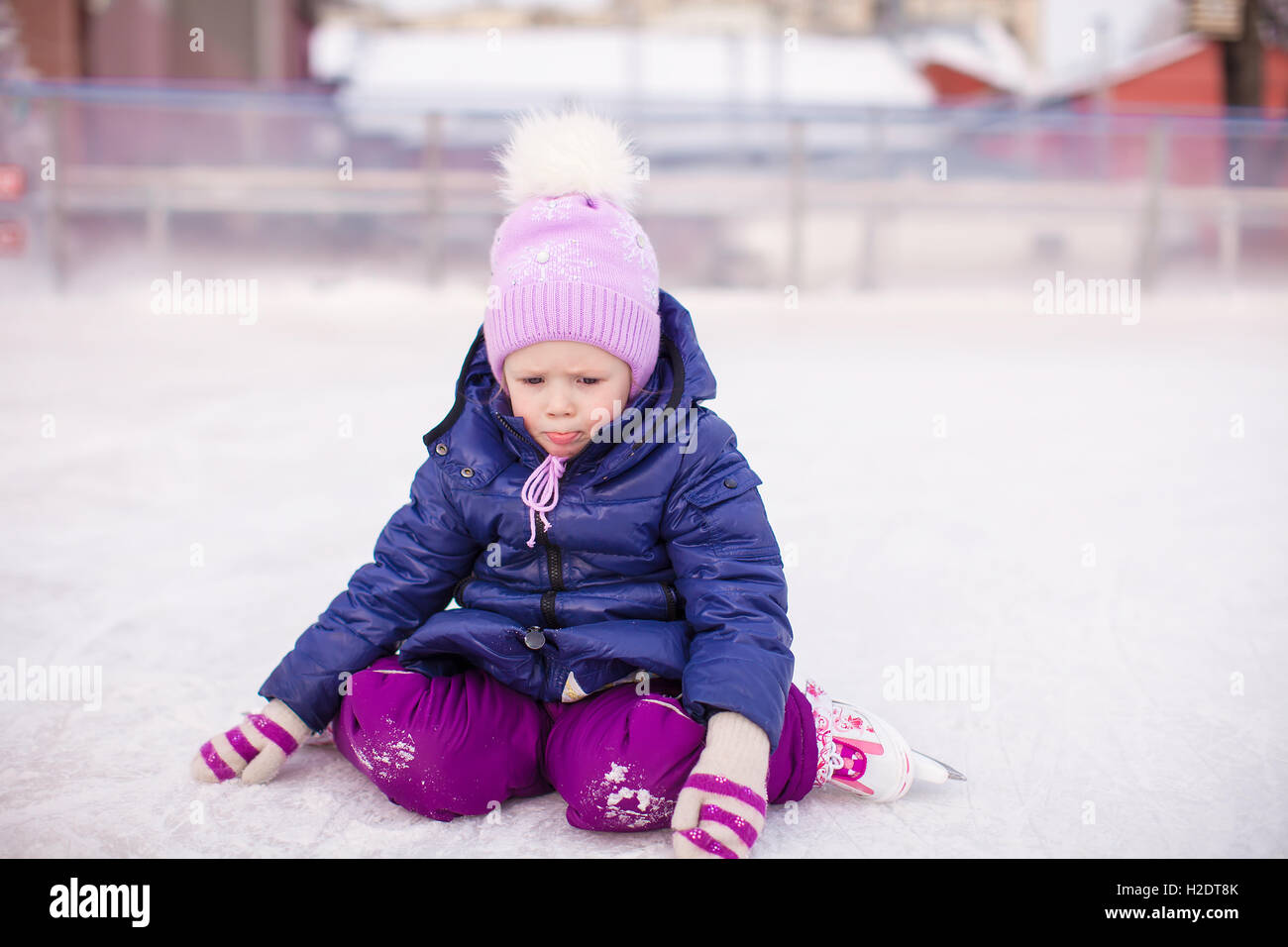 Little sad girl sitting on ice with skates after the fall Stock Photo ...