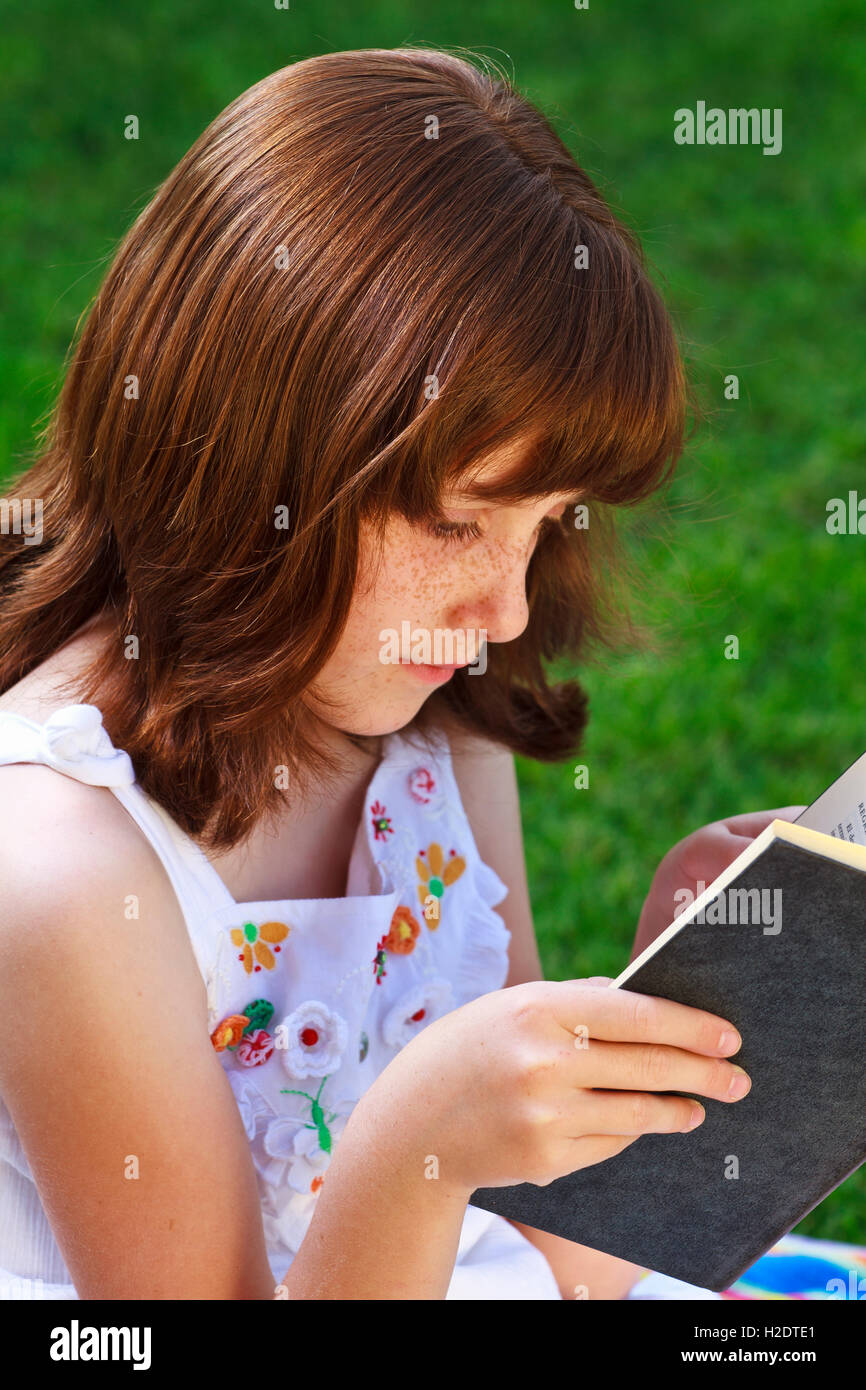 Young beautiful girl reading a book outdoor Stock Photo - Alamy