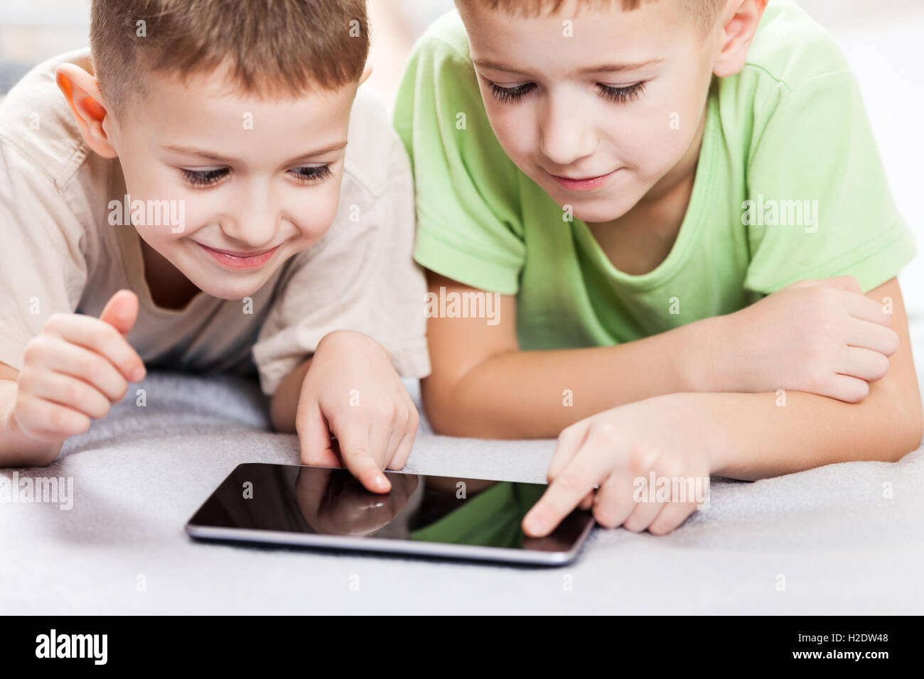 Two smiling child boys playing games or surfing internet on tabl Stock ...