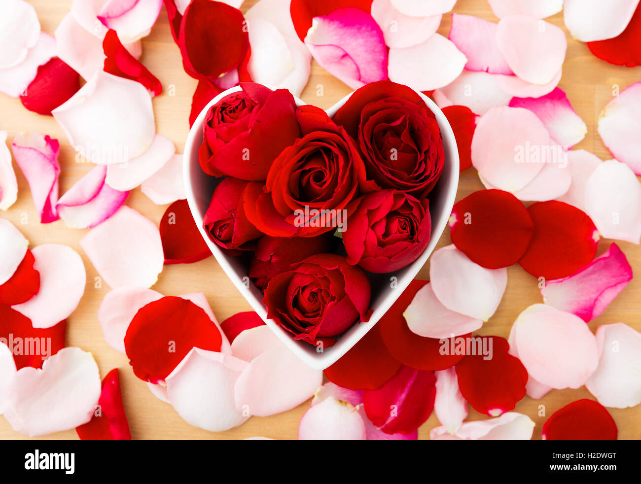 Red rose inside the heart shape bowl with petal beside Stock Photo - Alamy