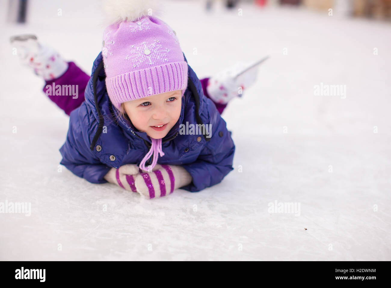 Adorable little girl sitting on ice with skates after the fall Stock ...