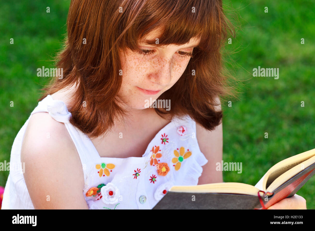 Young beautiful girl reading a book outdoor Stock Photo - Alamy