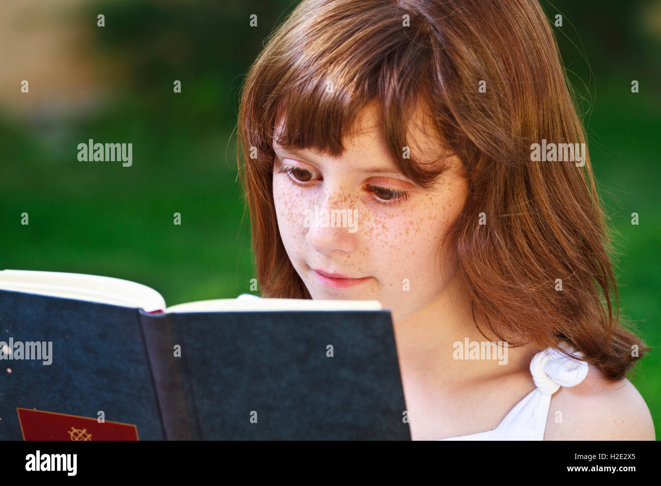 Literature.Young beautiful girl reading a book outdoor Stock Photo - Alamy