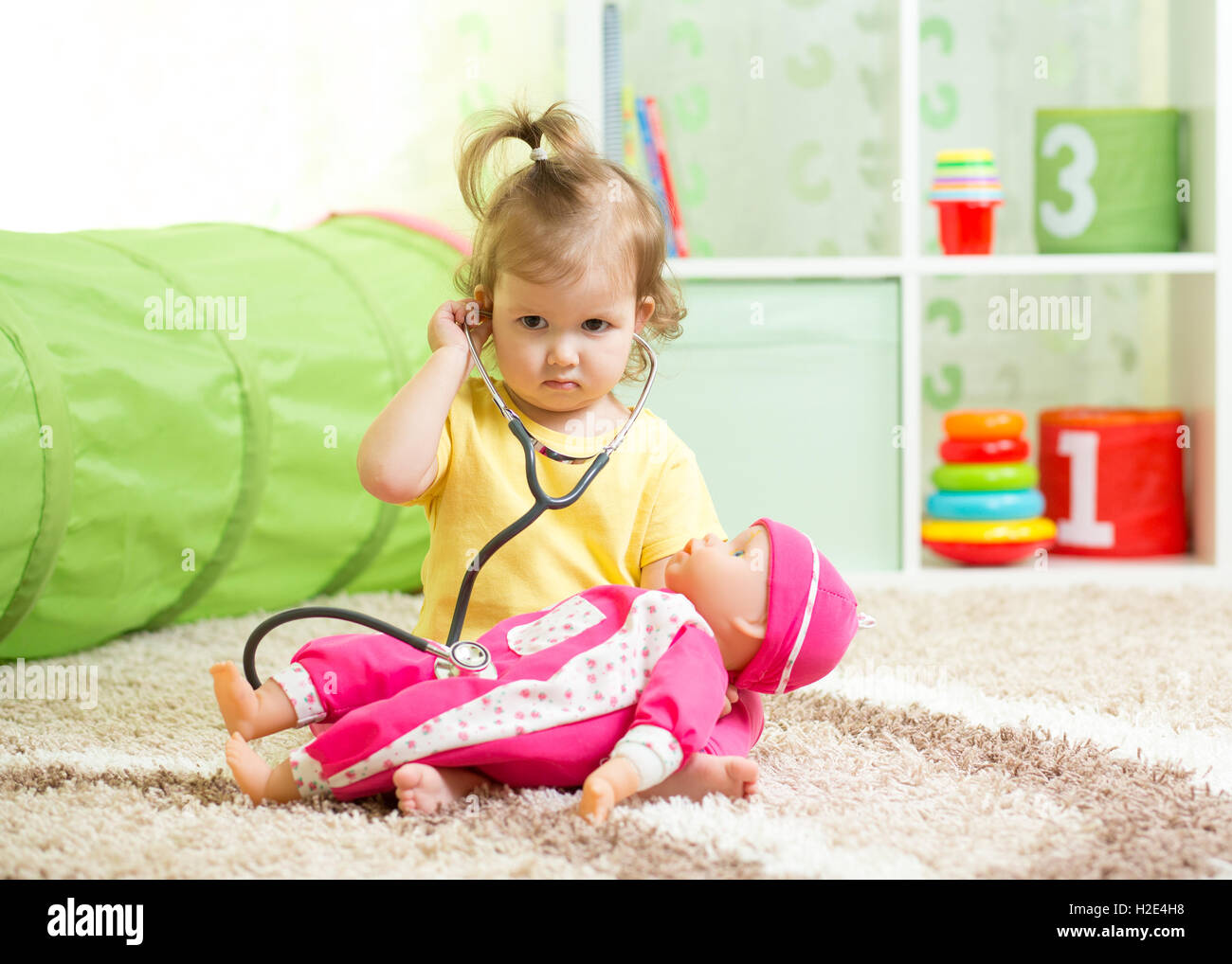 Kid Girl Playing Doctor With A Doll In Playroom Stock Photo - Alamy