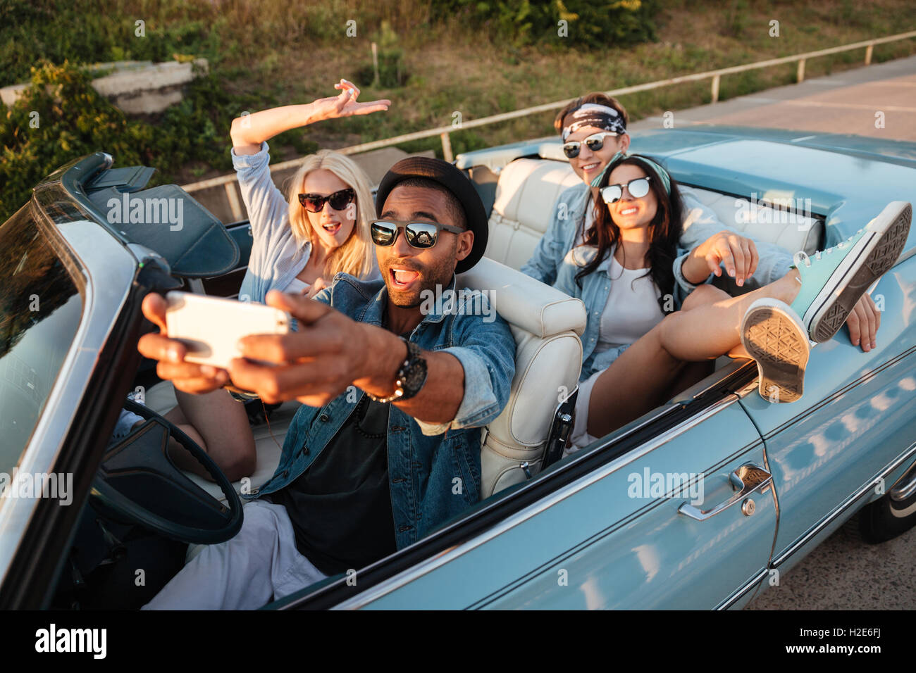 Multiethnic group of joyful young friends taking selfie with mobile ...
