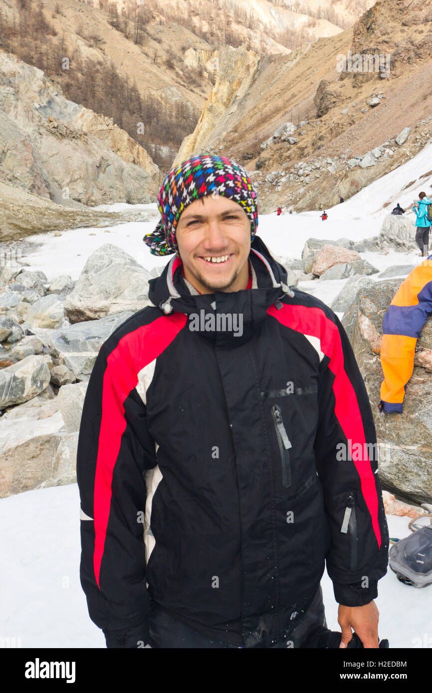 Portrait of a man smiling tourists in the snowy mountains in a black ...