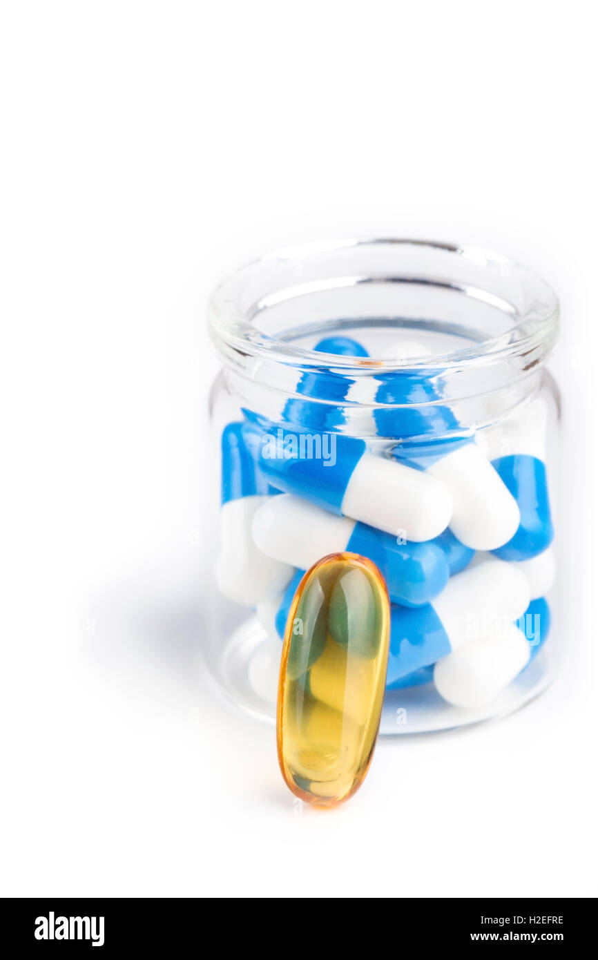 Blue white capsules in clear glass container with yellow pill Stock ...