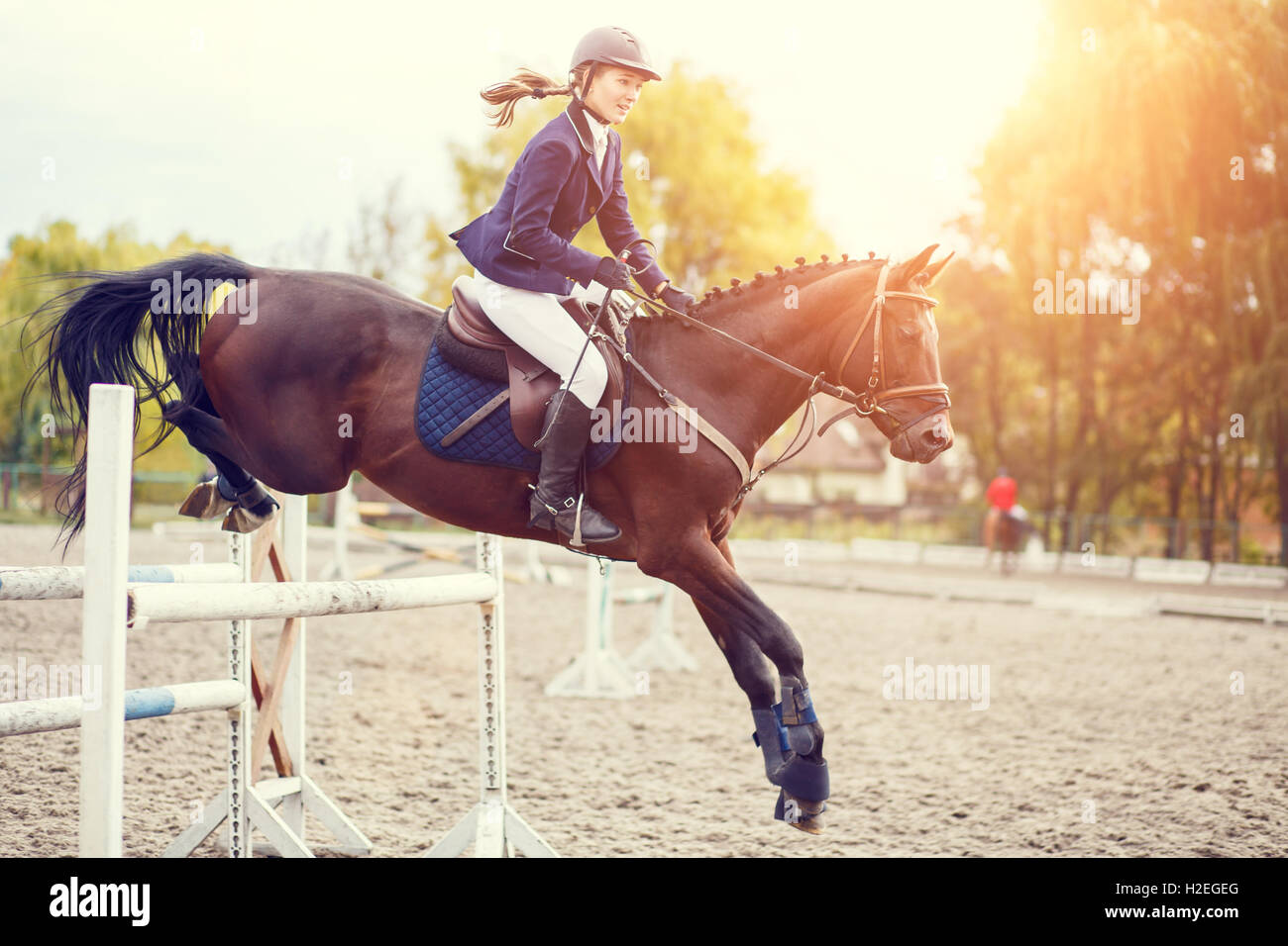 Young rider girl performing jump at horse show jumping competition ...