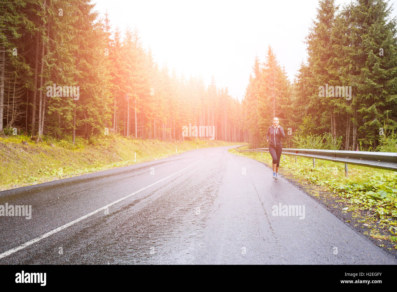 Young fitness woman with long hair running at the rainy morning in ...