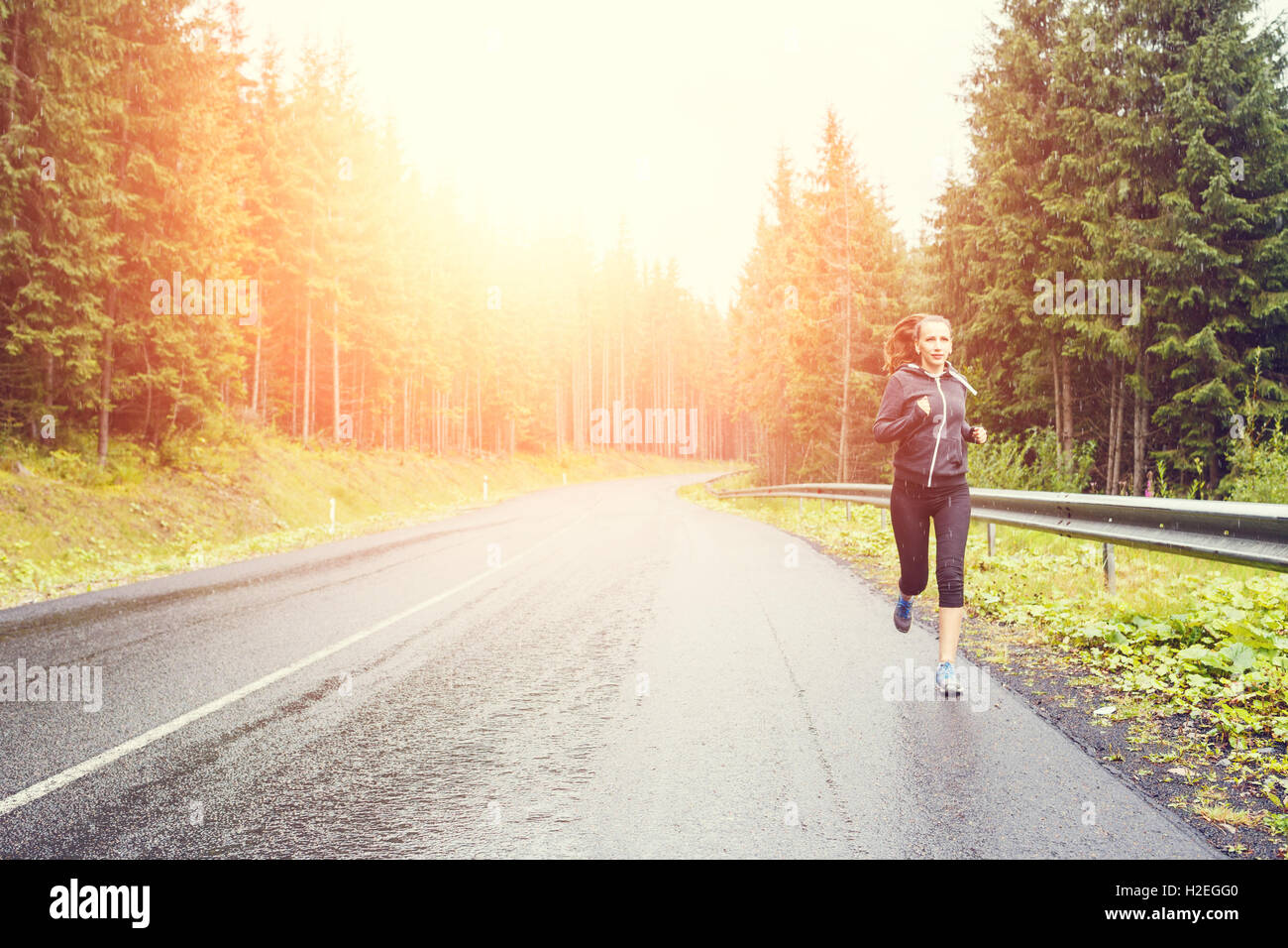 Young fitness woman with long hair running at the rainy morning in ...
