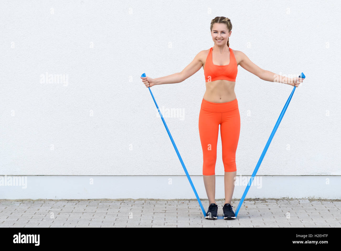 Young sporty woman doing core strengthening exercises using latex bands ...
