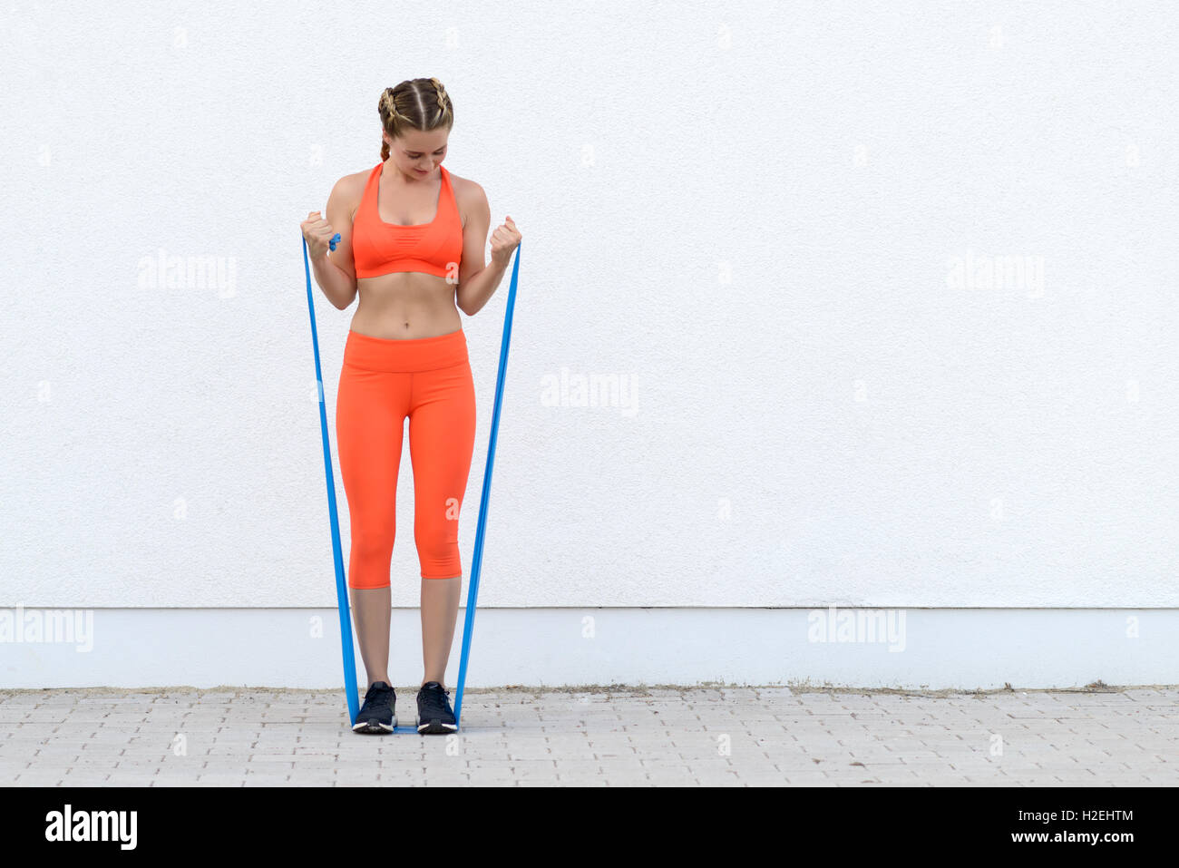 Young sporty woman doing core strengthening exercises using latex bands ...