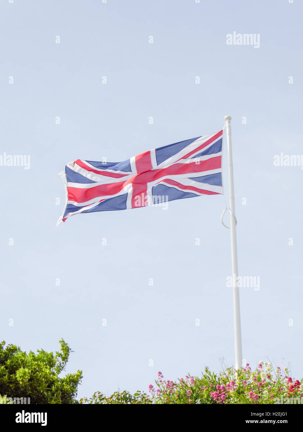 Union Jack flag flying over a blue sky background Stock Photo - Alamy