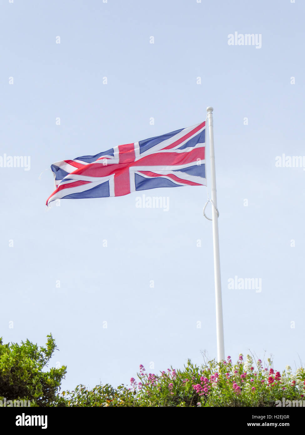 Union Jack flag flying over a blue sky background Stock Photo - Alamy