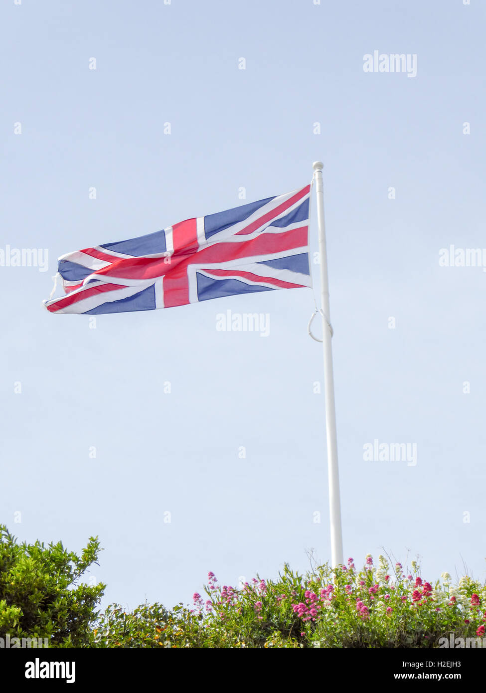 Union Jack flag flying over a blue sky background Stock Photo - Alamy