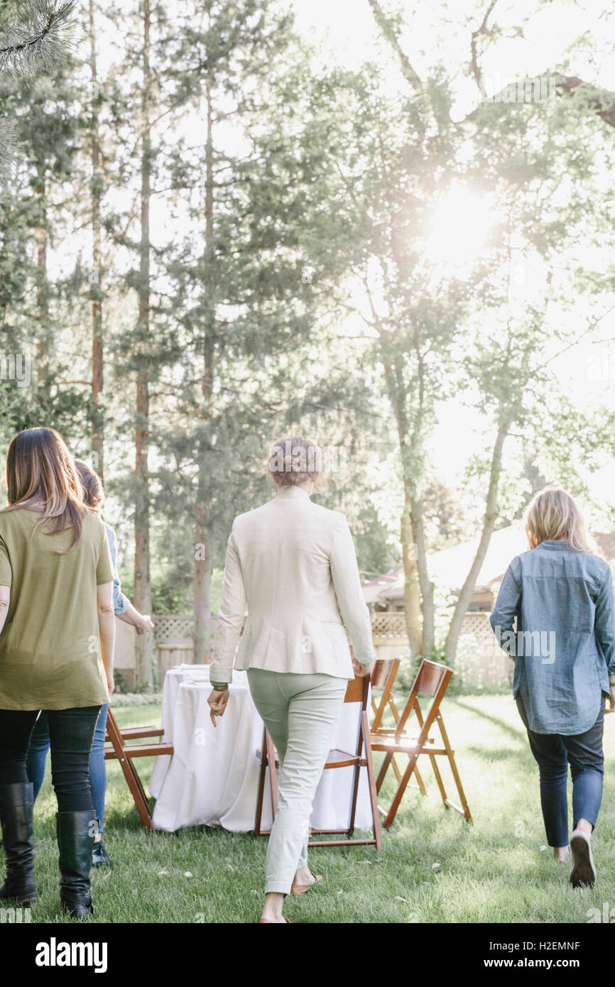 Three women walking towards a table and chairs in a garden Stock Photo ...