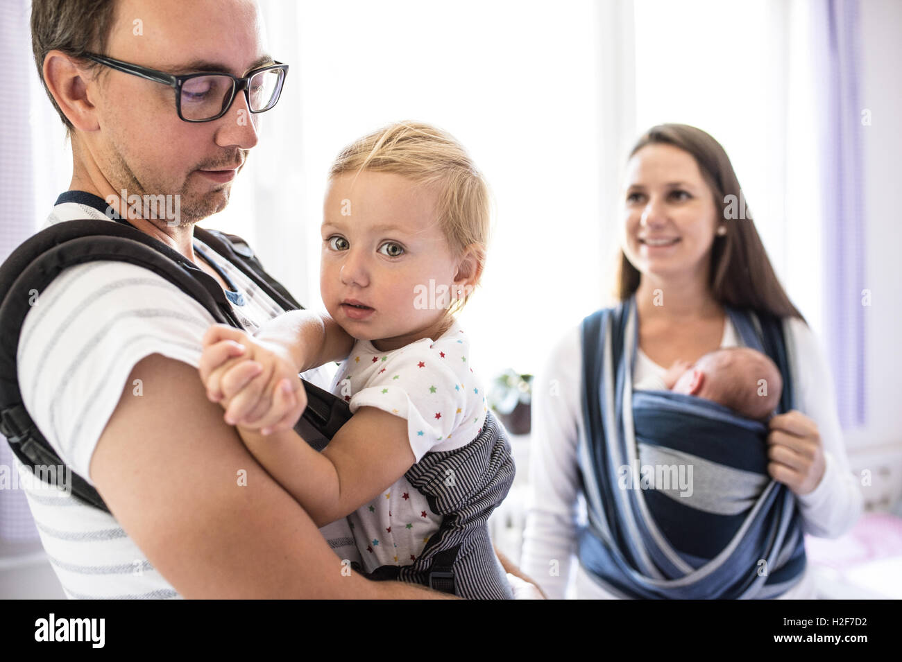 Young parents with children in sling and baby carrier Stock Photo - Alamy