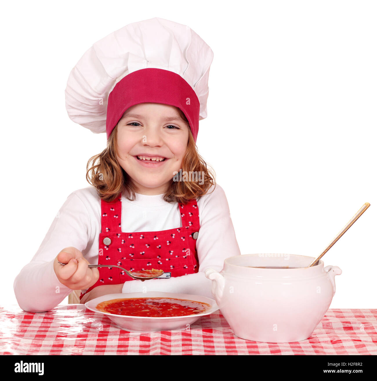 happy little girl cook eating soup Stock Photo - Alamy