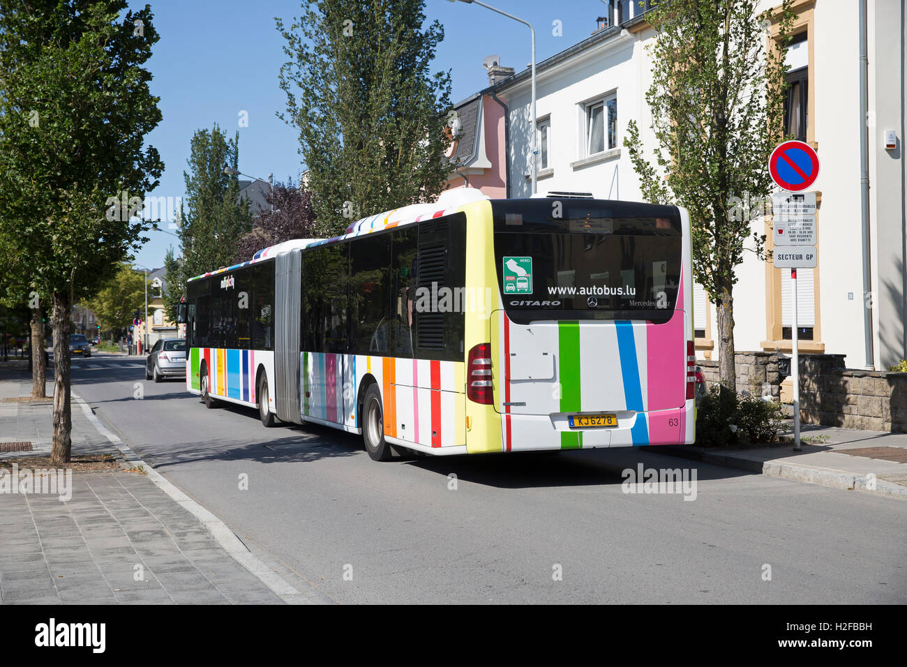 Multicoloured striped bendy bus travels through a street in Luxemburg ...
