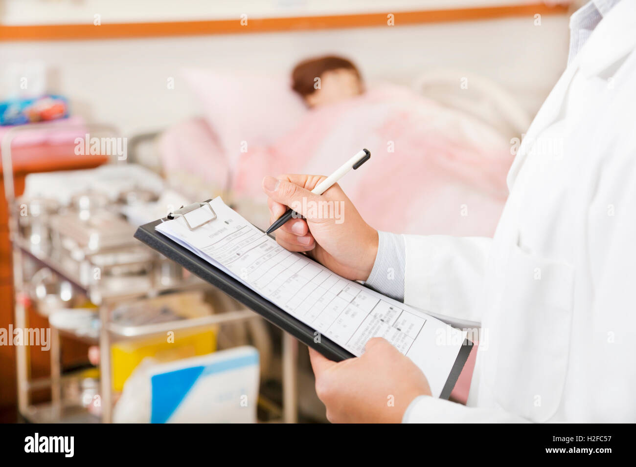 doctor writing on a medical chart with patient Stock Photo - Alamy