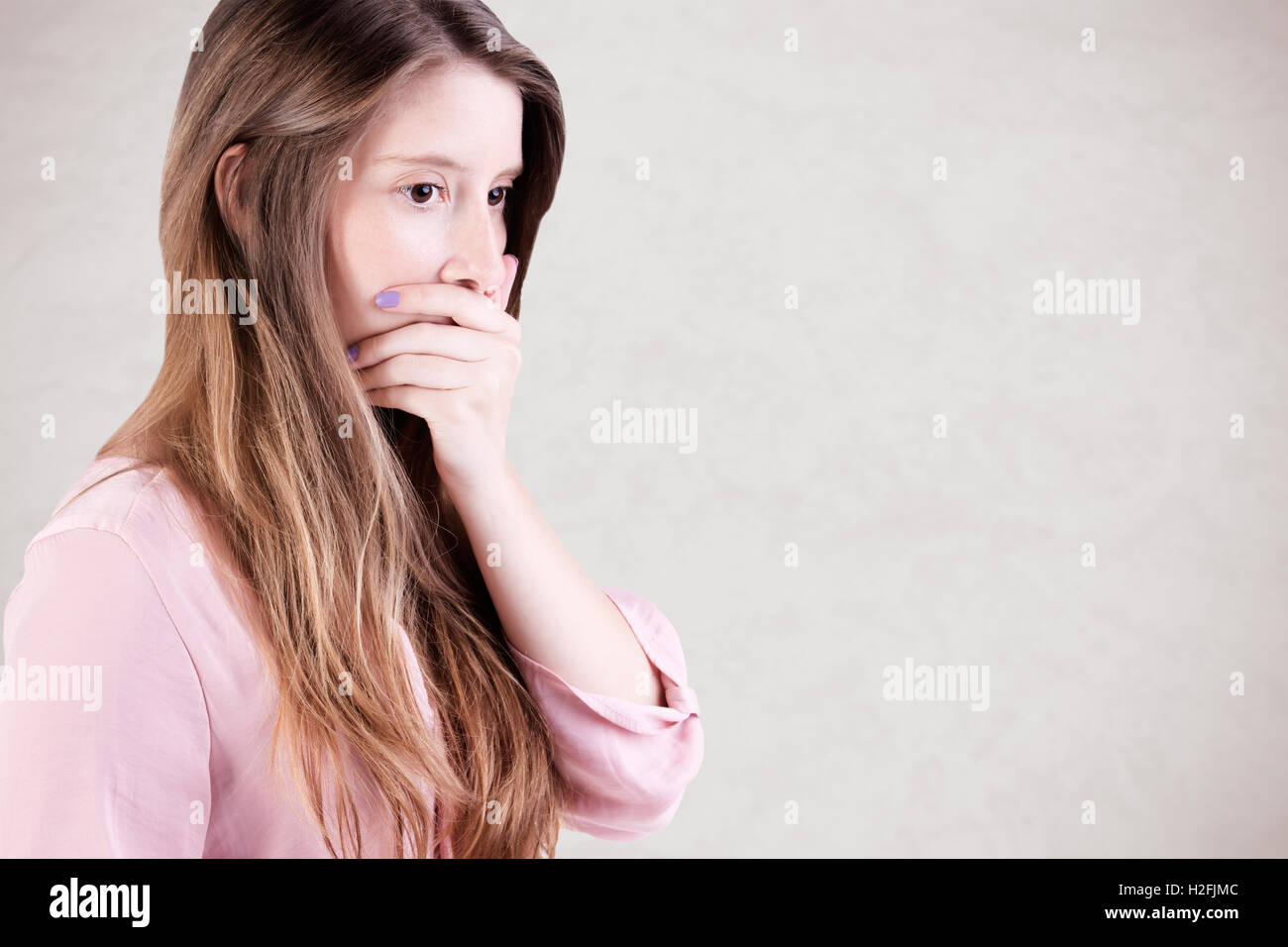 Closeup of a concerned woman covering her mouth, isolated in gray Stock ...