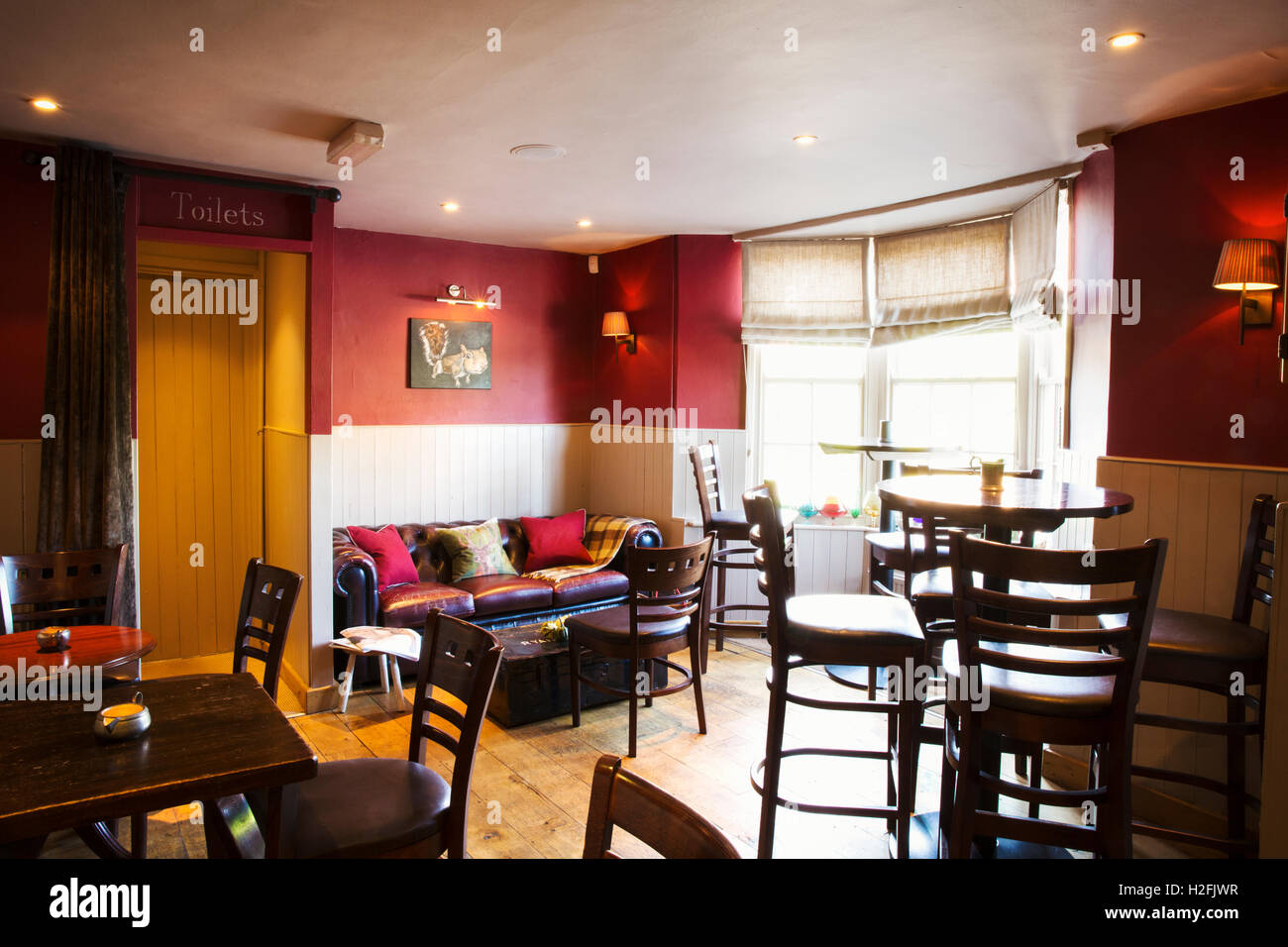 Village public house. Tables and chairs, and a sofa by a bay window ...