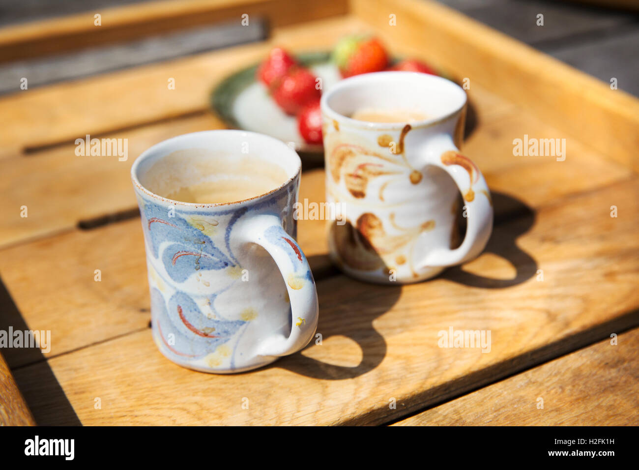 Two mugs and a plate of fruit on a garden table Stock Photo - Alamy