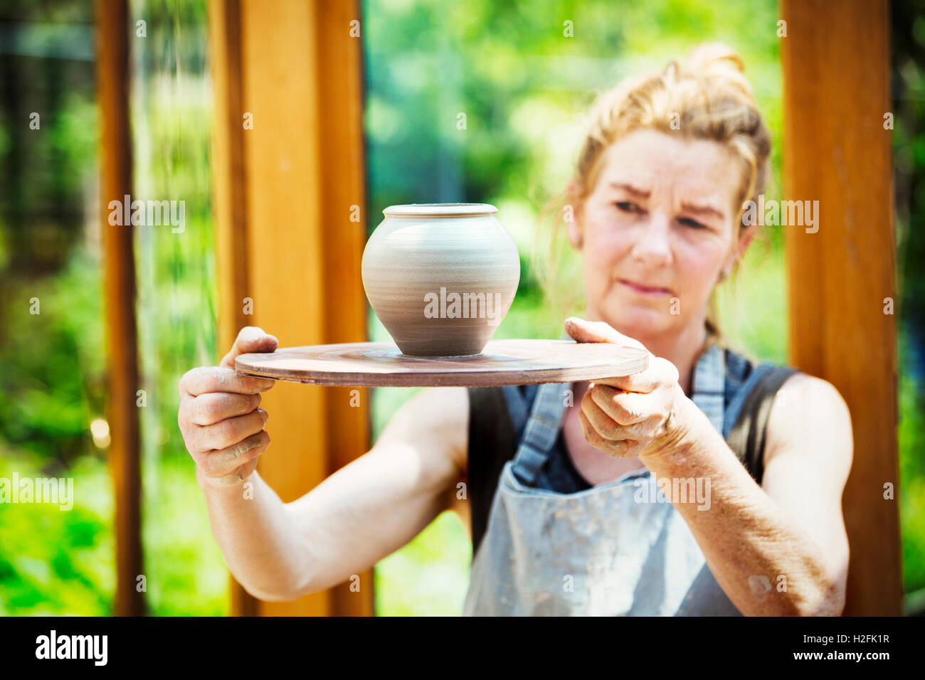A potter examining a hand thrown pot, wet clay slip, rounded vase with ...