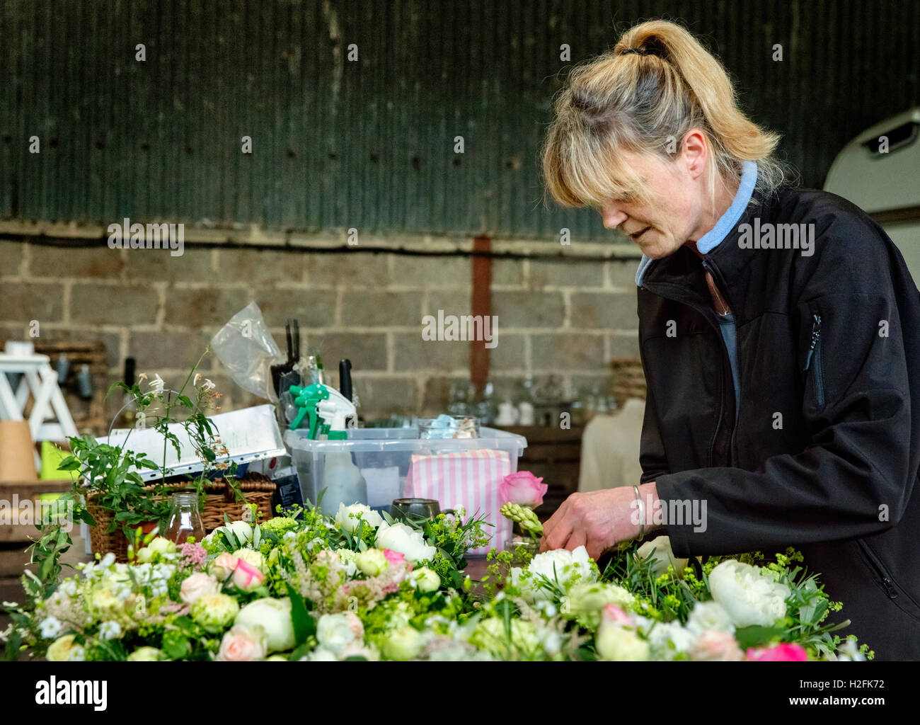 Commercial flower arranging. A woman florist working at a bench on ...
