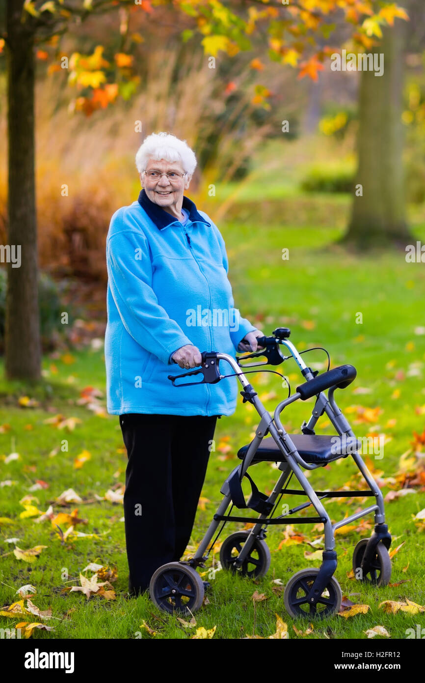 Happy senior handicapped lady with a walking disability enjoying a walk ...