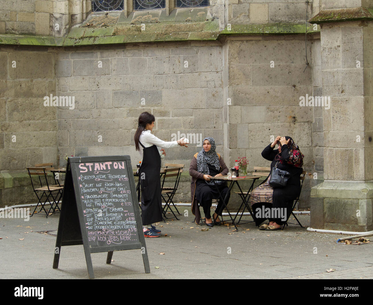 Two muslim women at a outdoor cafe table in the city center of Cologne ...