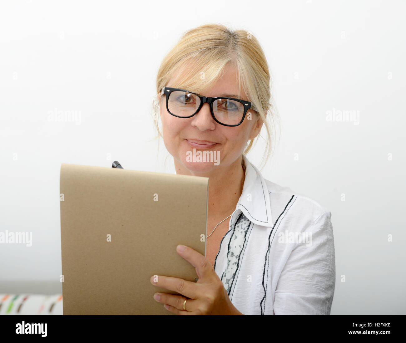 a mature woman writing on a notebook Stock Photo - Alamy