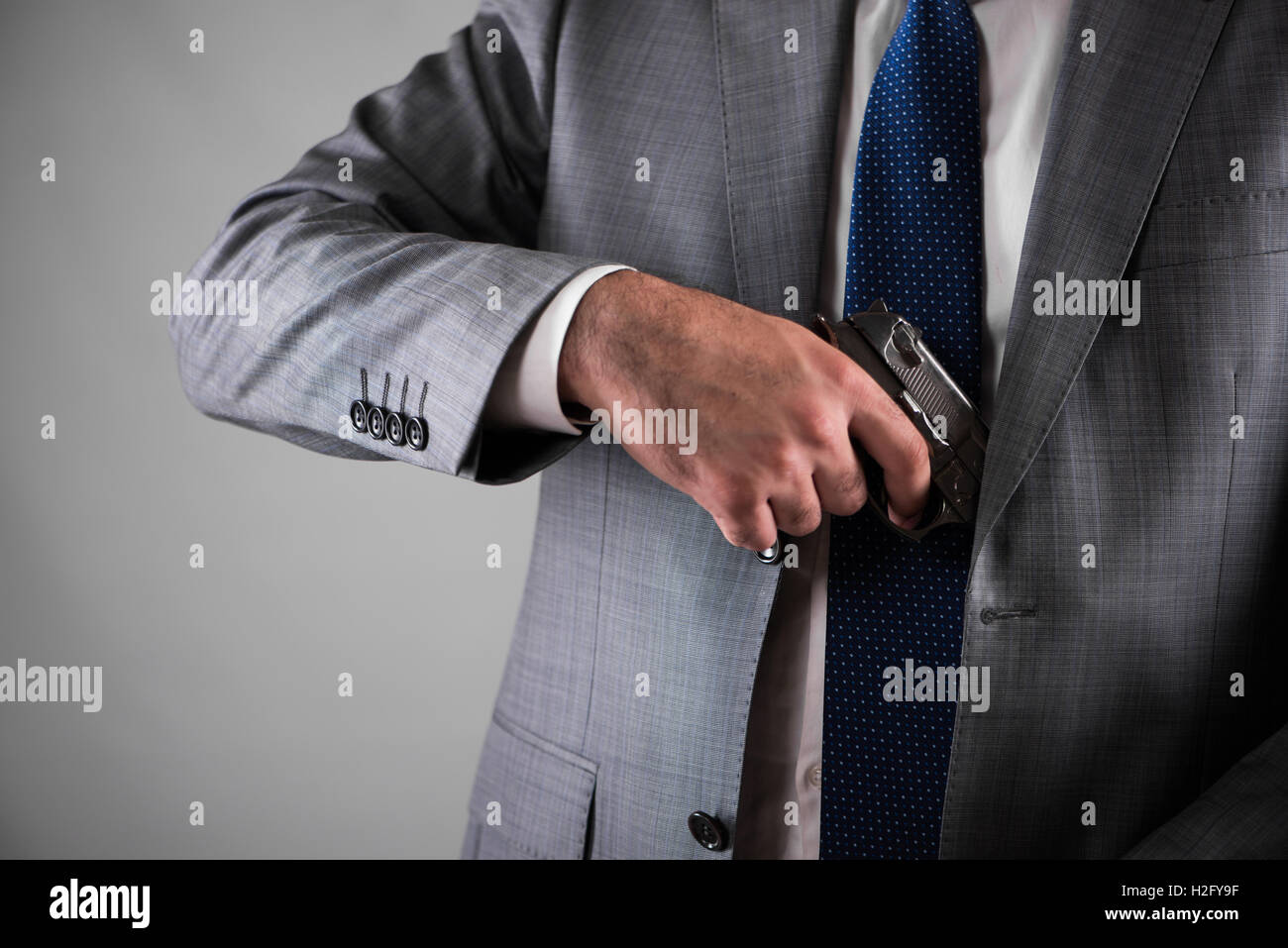 Man pulling out gun from his pocket Stock Photo - Alamy