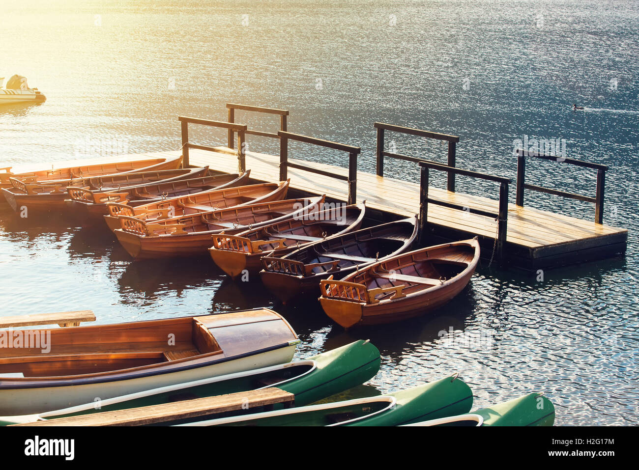 Small wooden boats and canoes docked and tied to empty pier on the lake ...