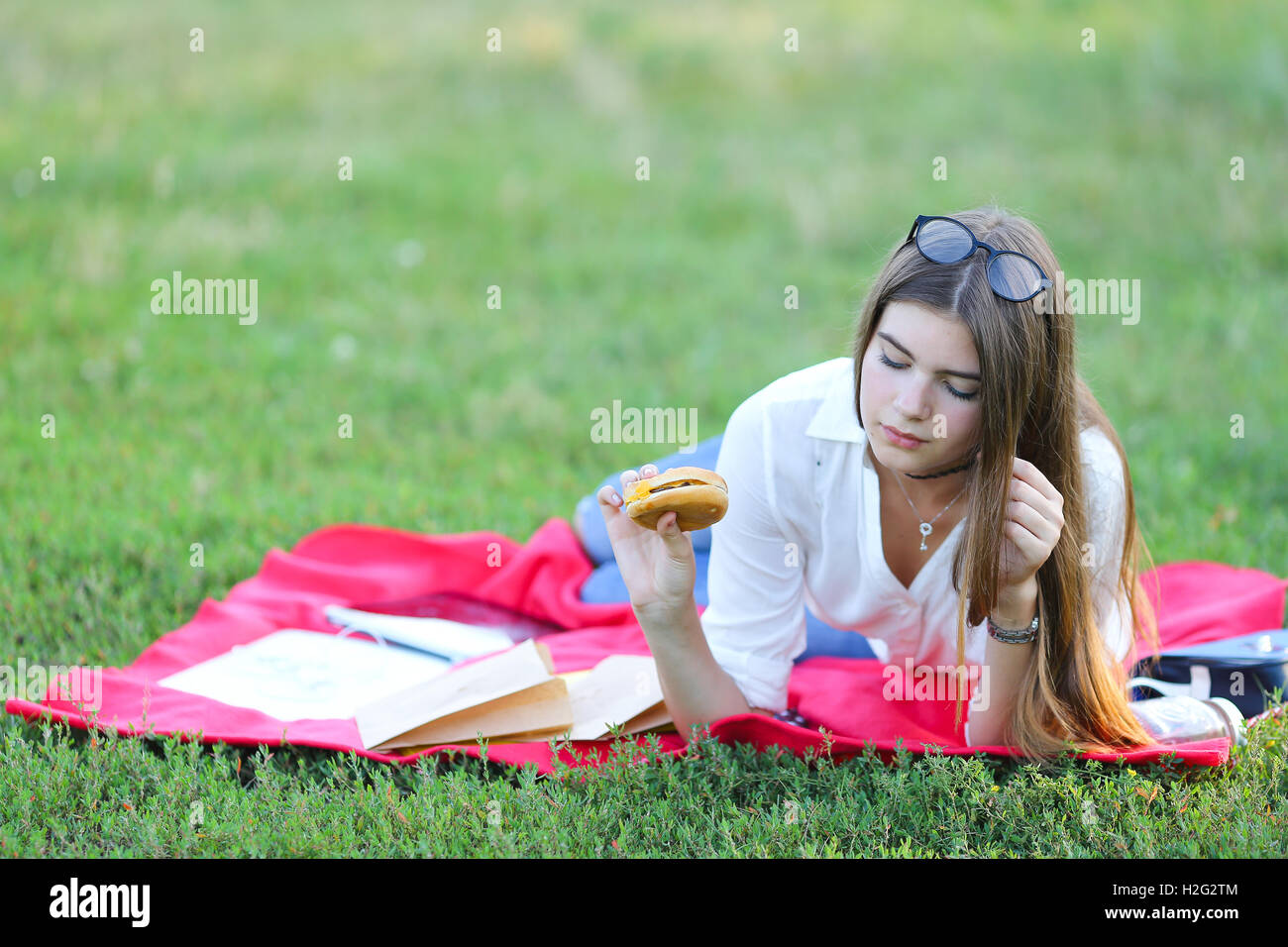 girl lying on the nature and eateth fast food. student working in the ...