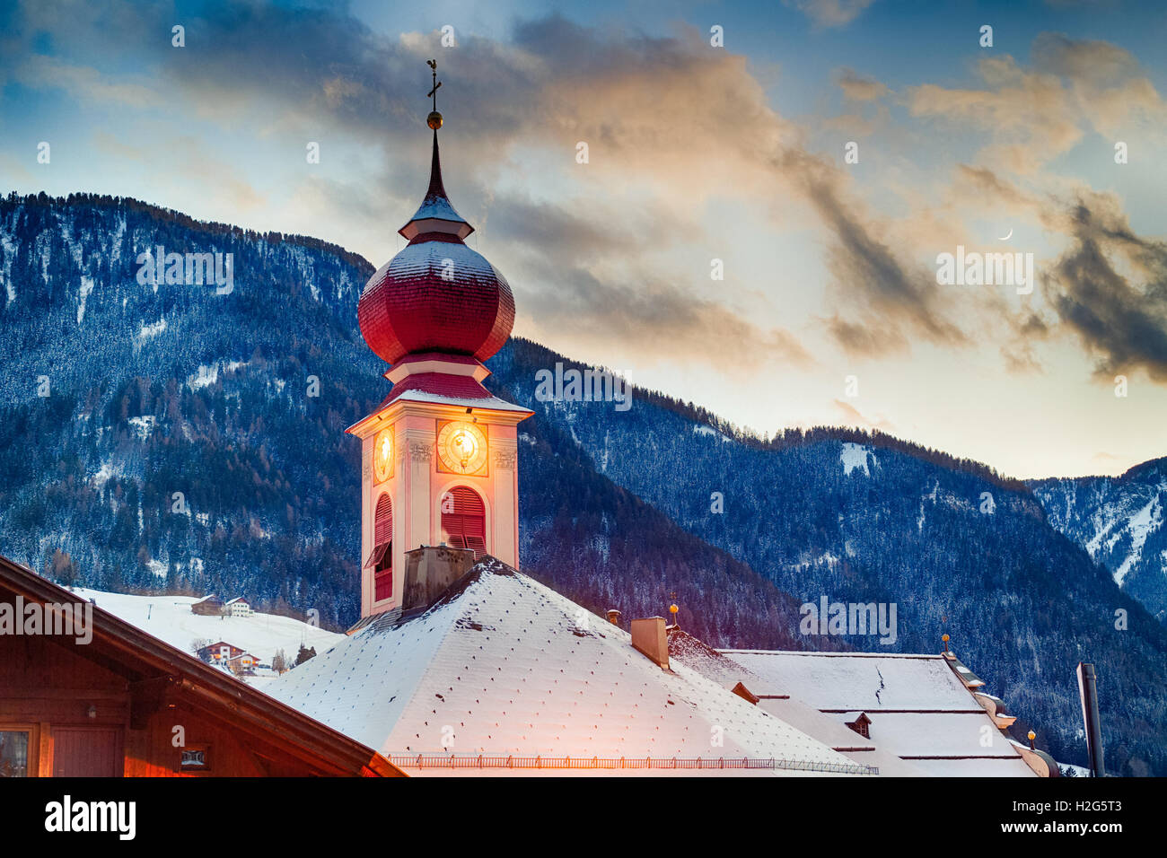 clock tower of church in alpine village in Italy at dusk Stock Photo ...