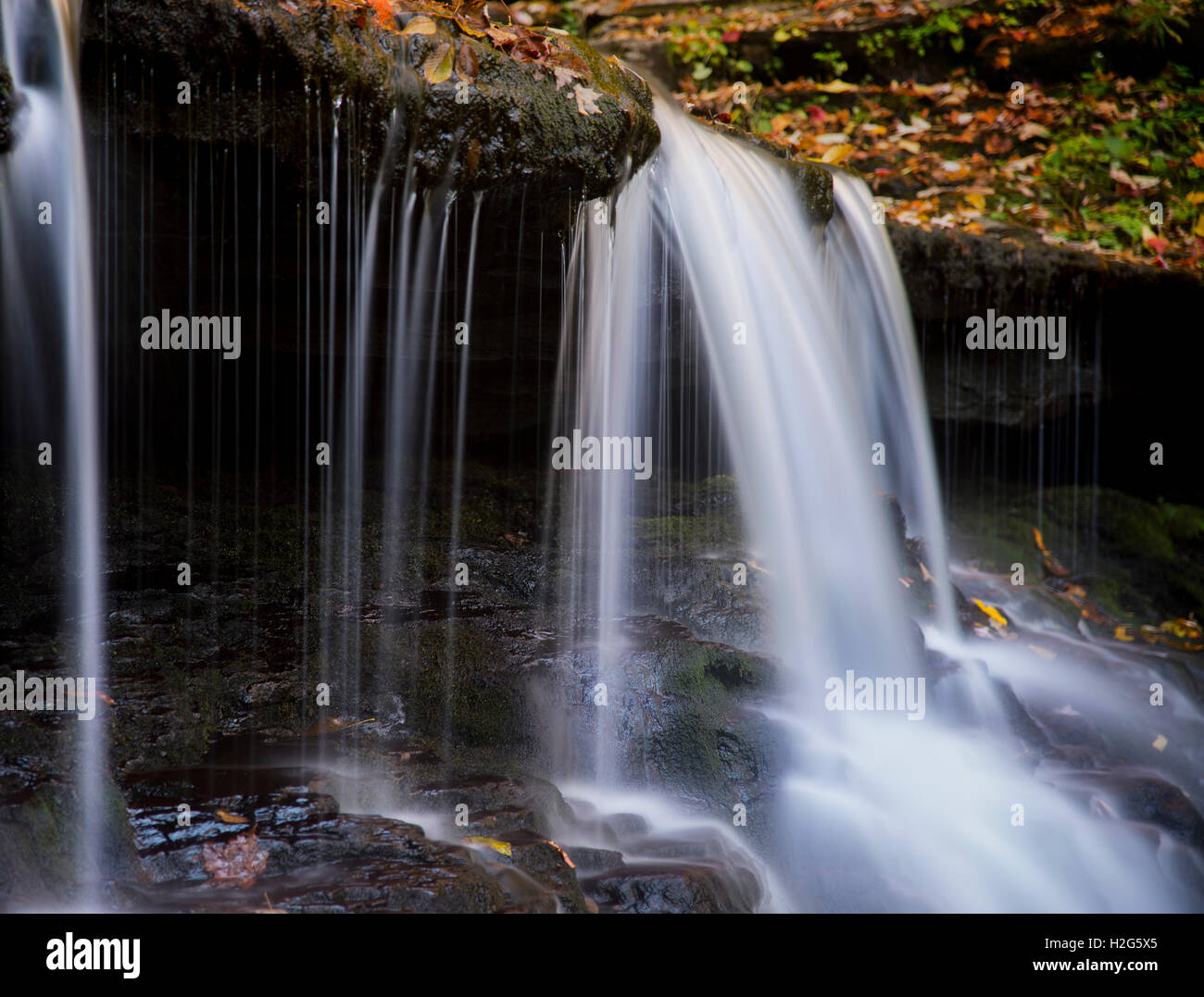 A small waterfall surrounded by bright fall colors Stock Photo - Alamy