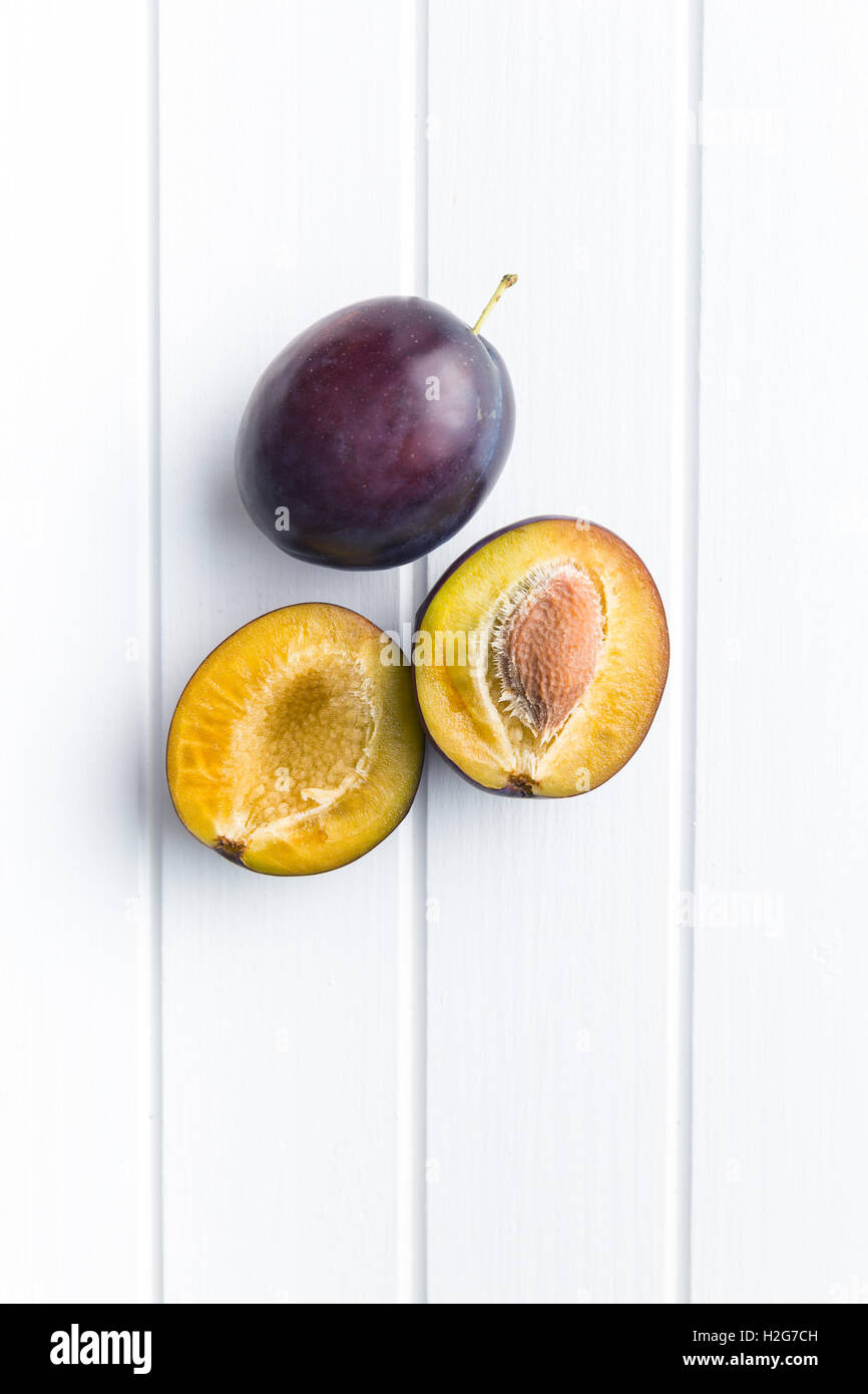 Halved ripe plums on kitchen table. Top view Stock Photo - Alamy